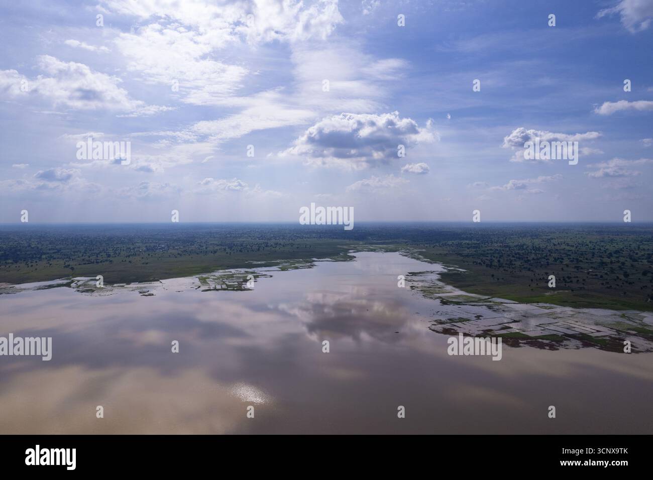 Aerial view of the winding, muddy river reflecting the wispy clouds ...