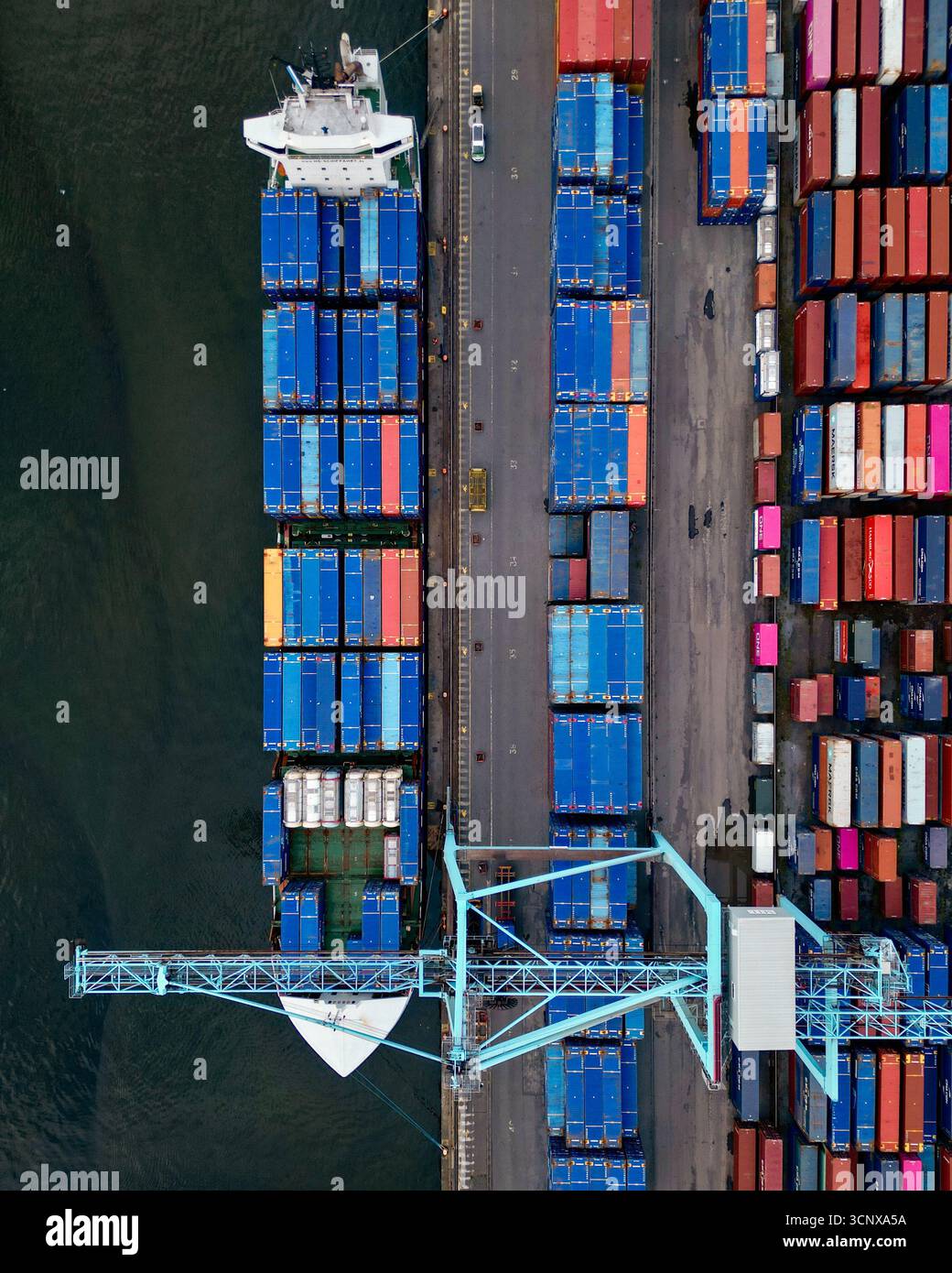 Aerial view of a colossal cargo ship moored alongside a bustling dock ...