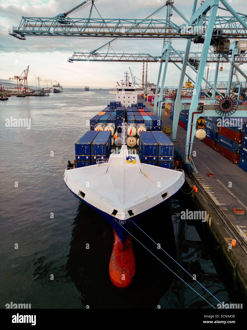 Aerial view of a cargo ship laden with blue containers moored beside ...