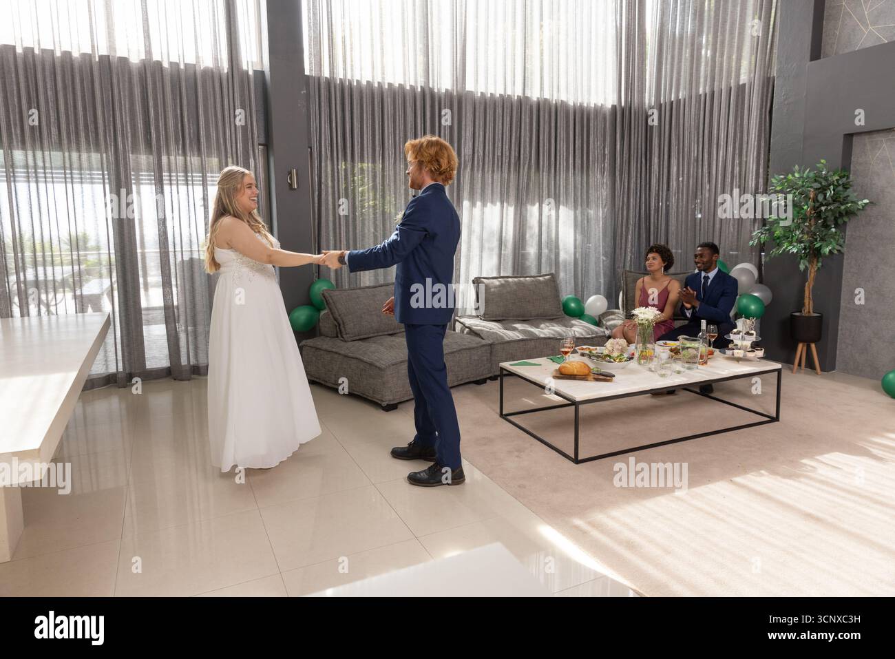 Wedding couple holding hands, facing each other in lounge while guests ...