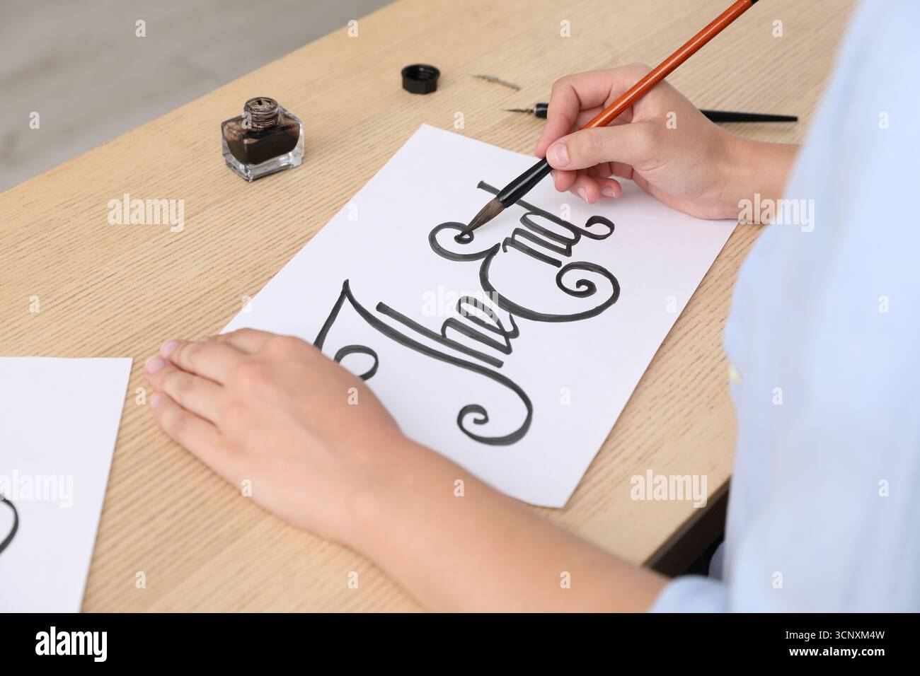 Calligraphy. Woman with brush writing words The End on sheet of paper ...