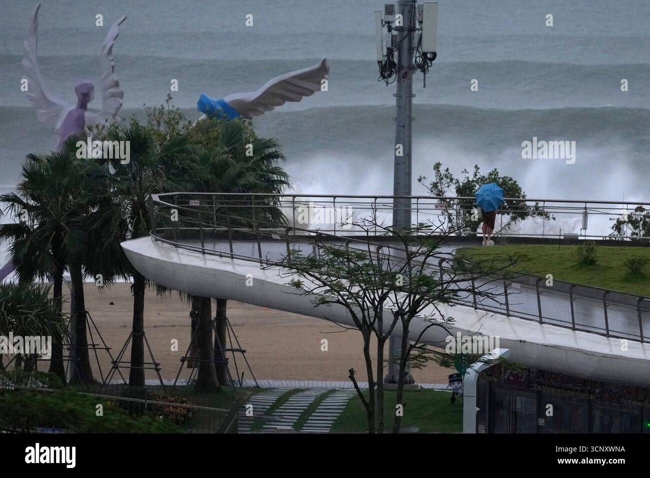 A woman watches waves crashing ahead of Super Typhoon Ragasa in ...