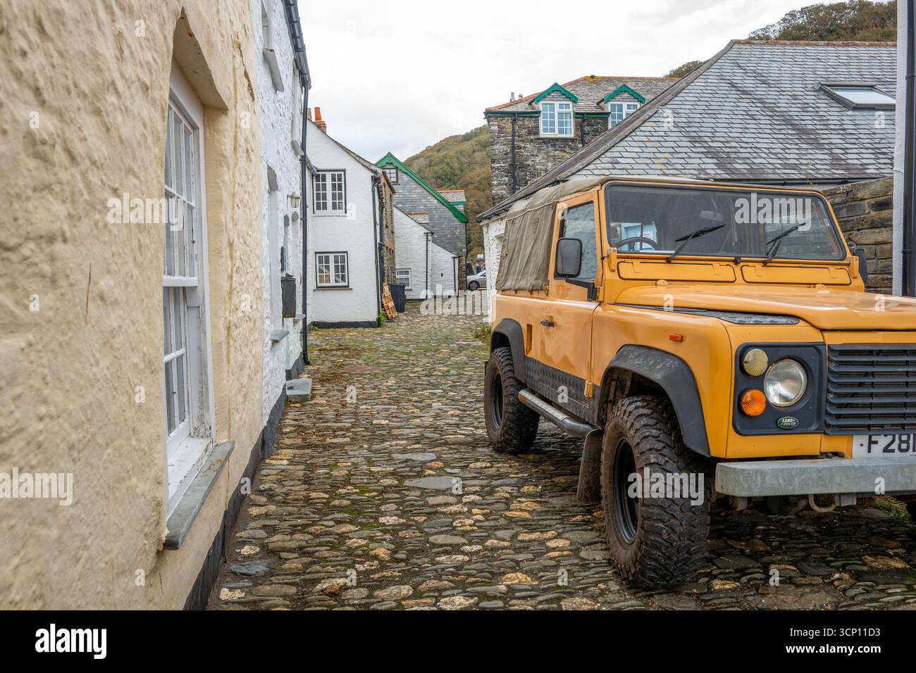 Orange painted Landrover Defender pickup vehicle parked in the narrow ...