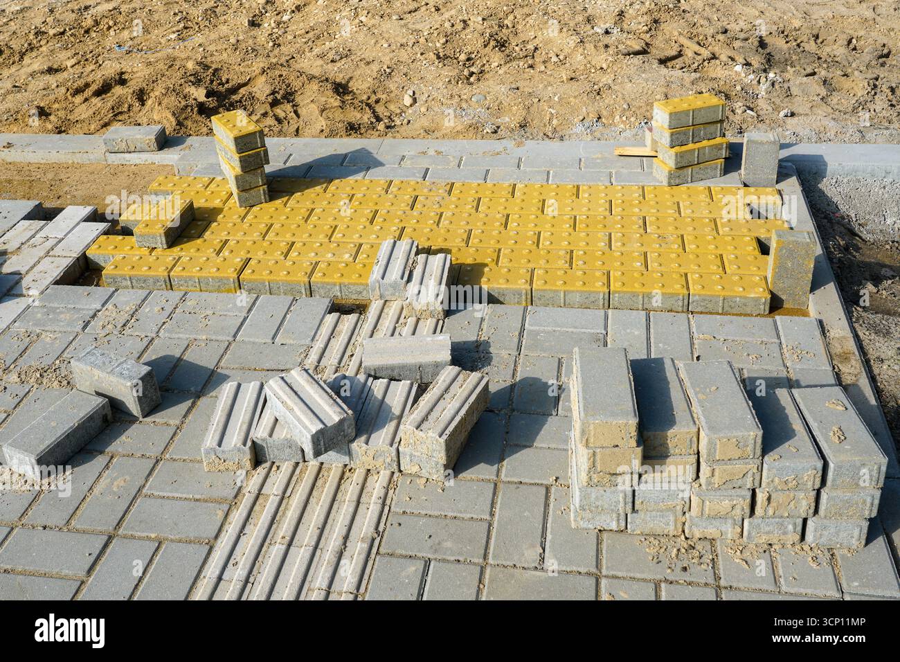 Construction of tactile paving with yellow and gray concrete tiles for ...