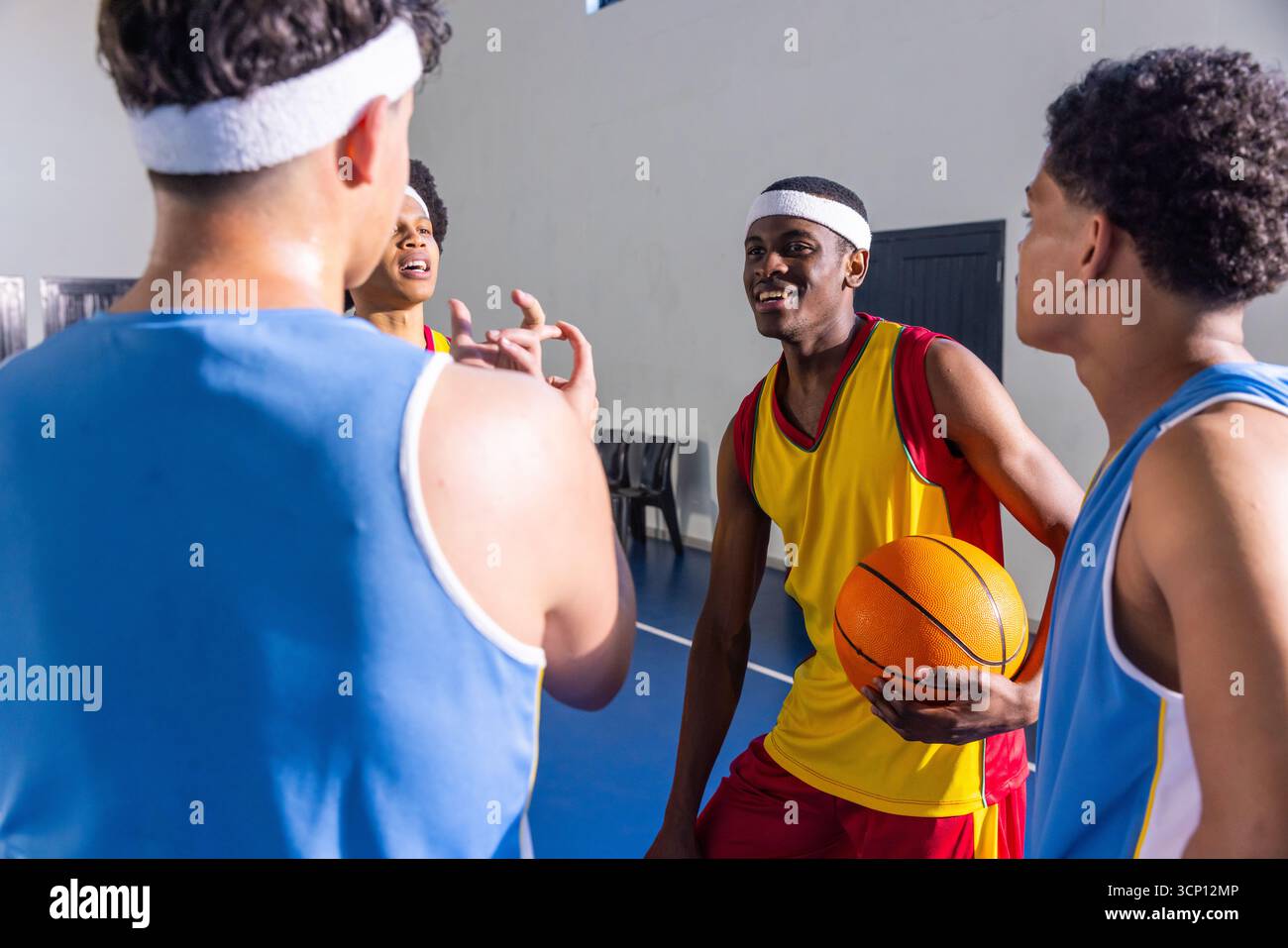 Diverse male teenage basketball players in jerseys standing at gym ...