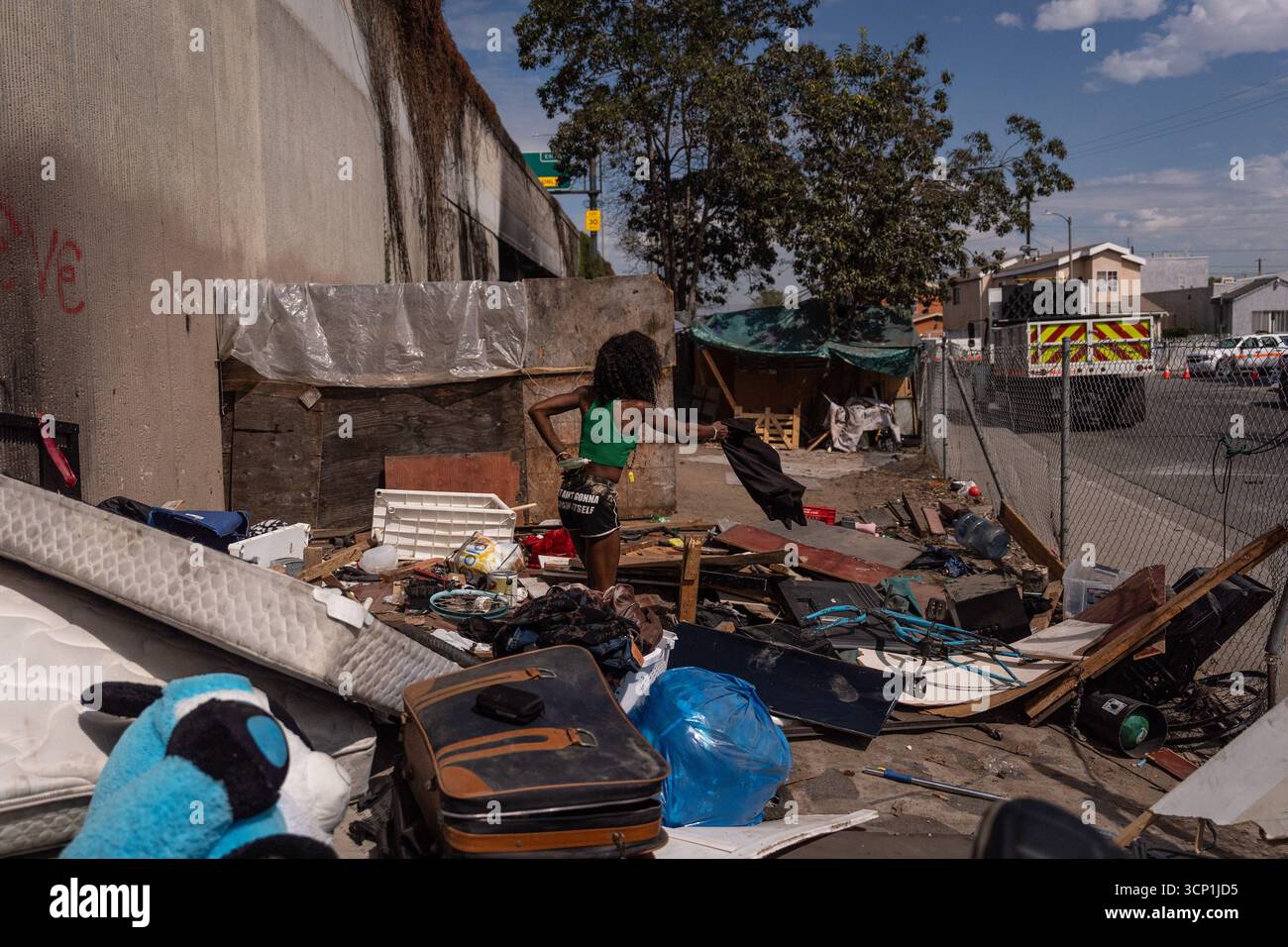 Sheena Long uses a T-shirt to shoo away flies as workers clear a ...