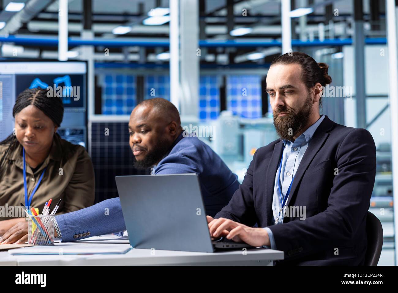 Photovoltaics factory engineers using software on laptop to improve ...