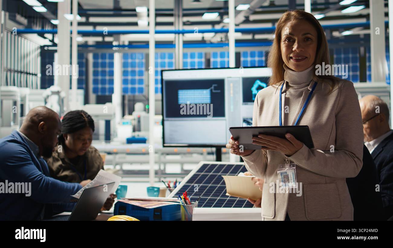 Portrait of smiling scientist in factory using tablet to check PV ...