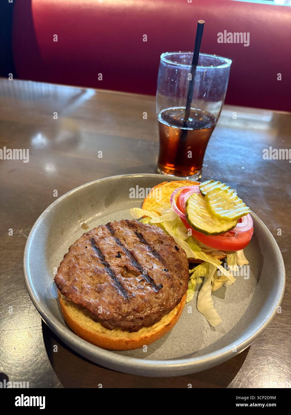 An open-faced grilled beef burger with lettuce, tomato, red onion, and ...