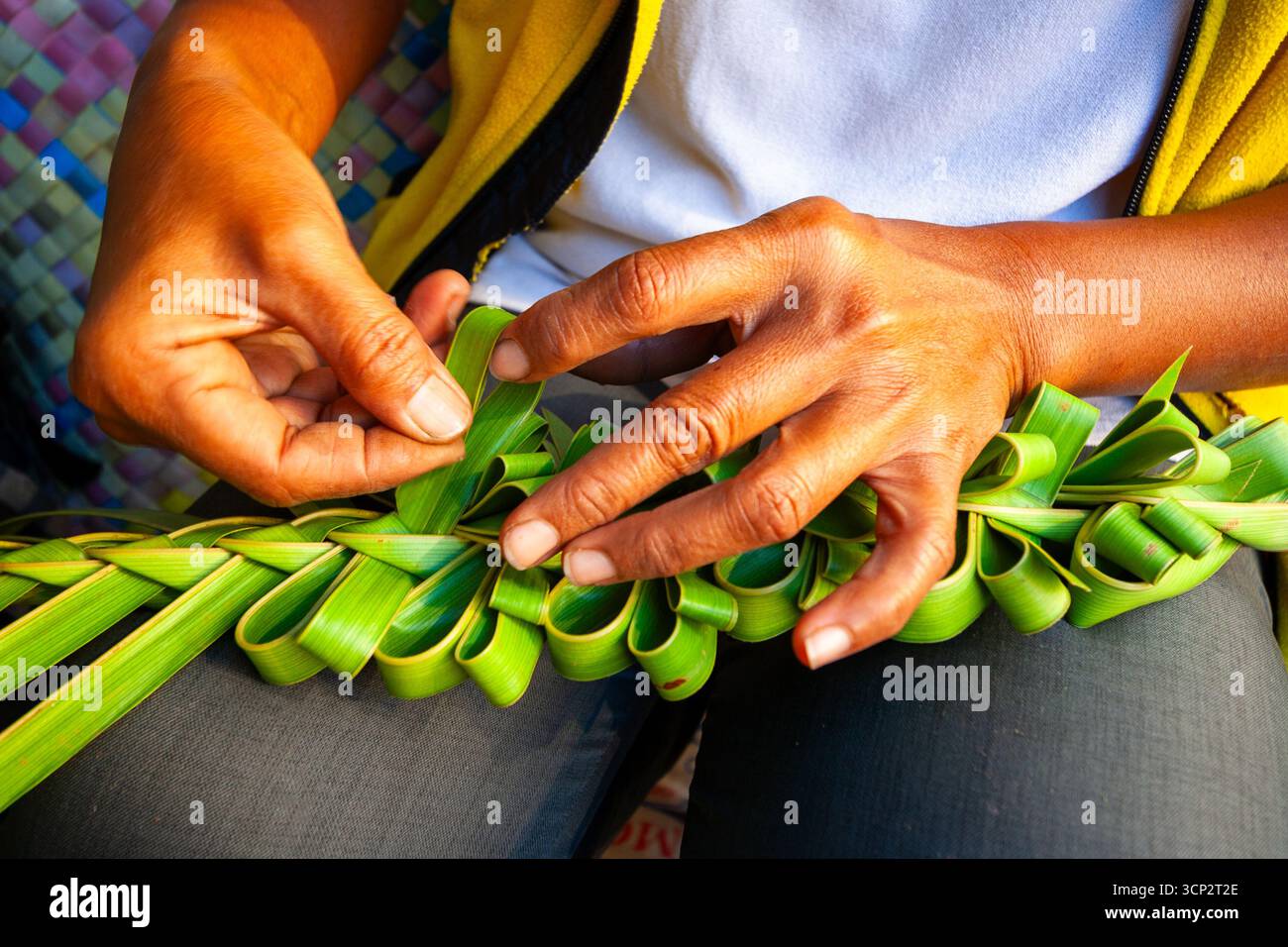 A Filipino making artistic coconut palm frond wreaths for sale outside ...