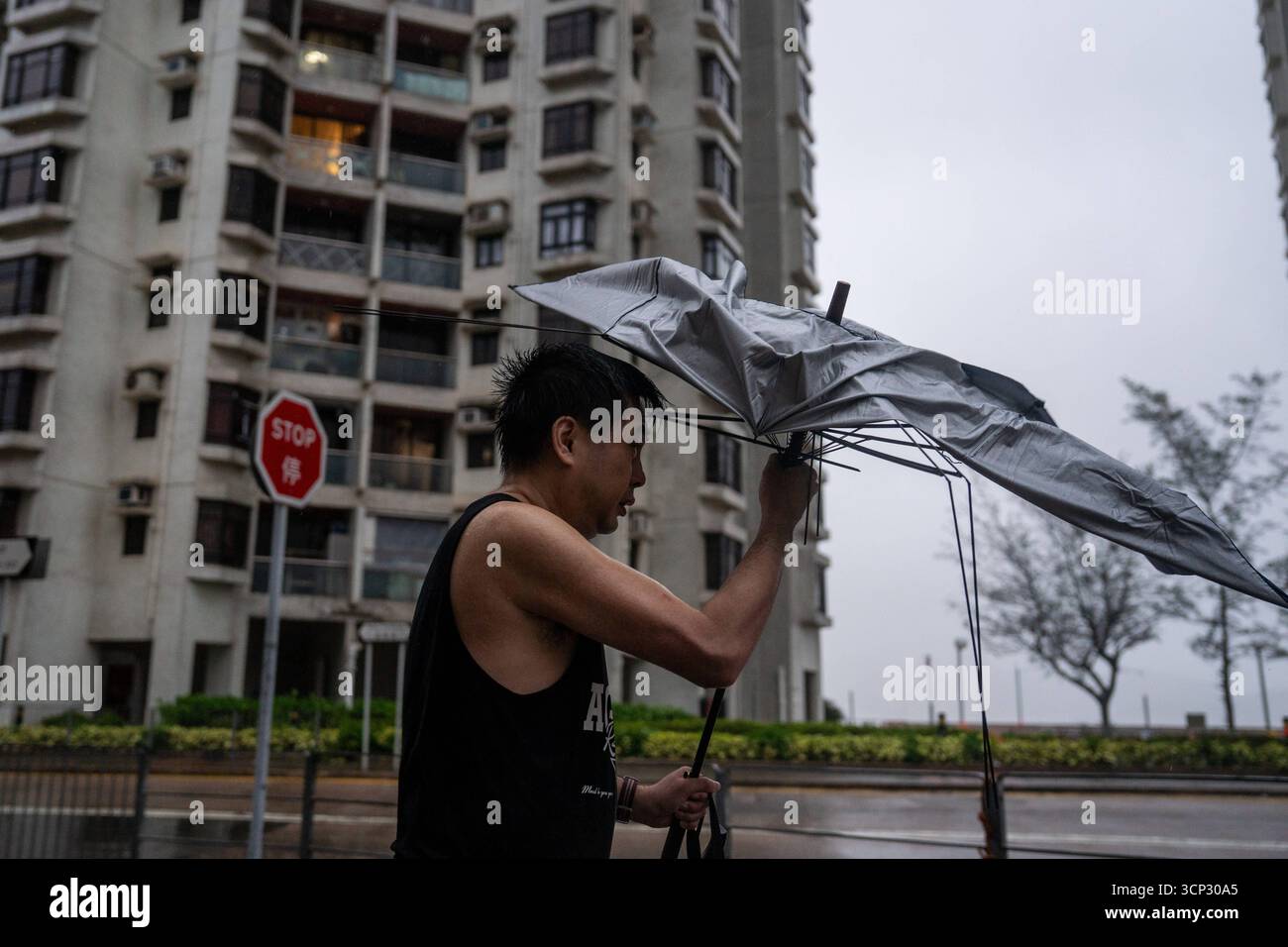 Hong Kong During Typhoon Ragasa A man holding a broken umbrella ...