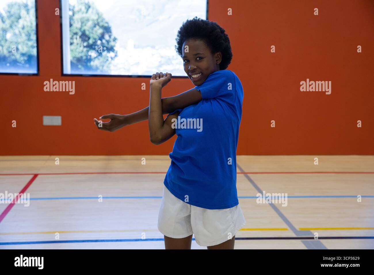 African american child stretching arm across chest on gym floor with ...