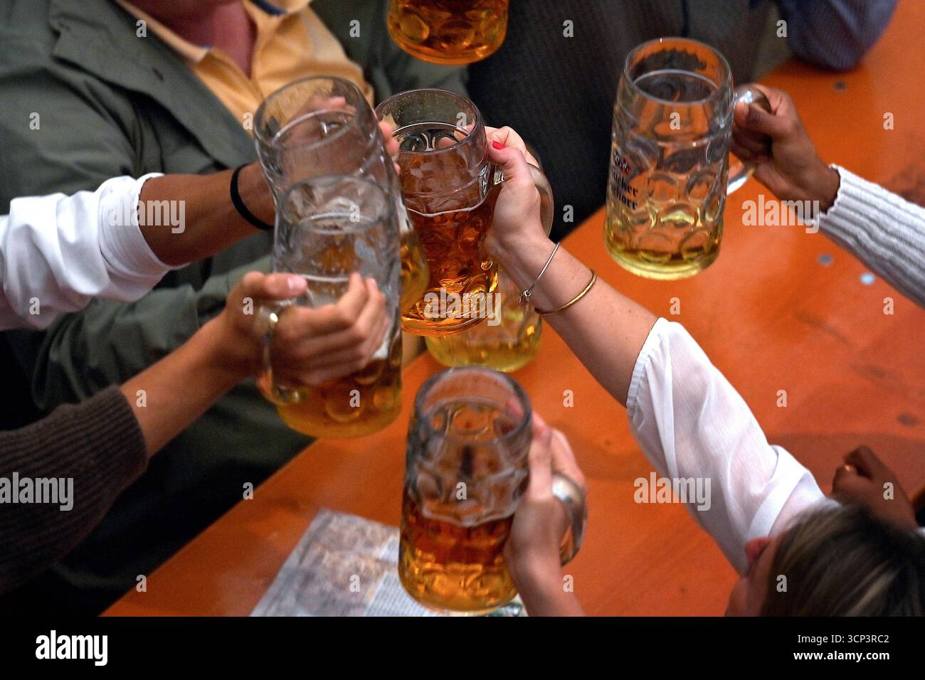190.Oktoberfest 2025. Besucher,Gaeste prosten sich mit Masskruegen zu ...