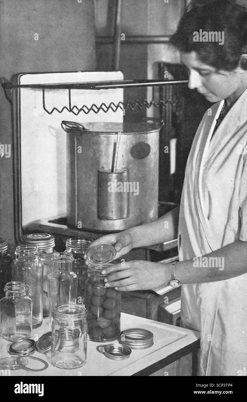 A lady with various glass jars on an enamel worktop. Behind her is a ...