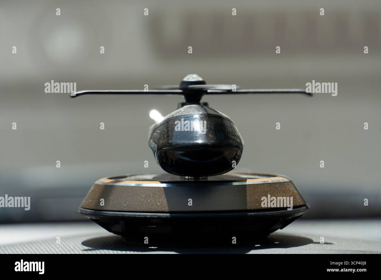 Close-up of a dusty helicopter-shaped car air freshener on a dashboard ...