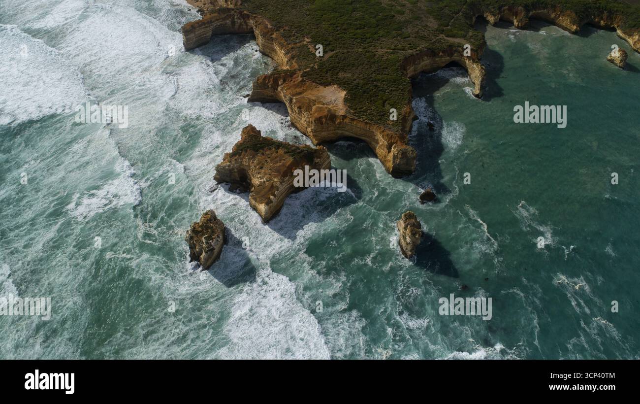 Aerial view of rugged cliffs meet the turquoise sea, waves crashing ...