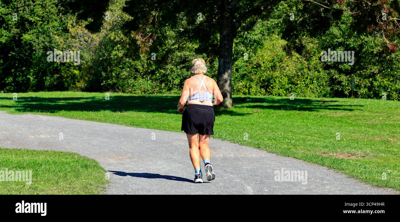 Mature older woman running along a path, Cosmeston Lakes and |Country ...