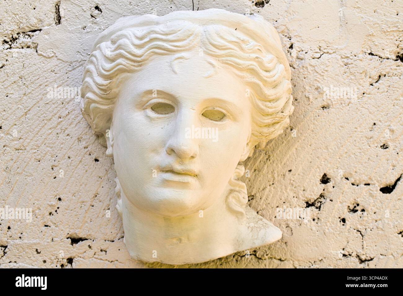 A white statue of a woman's head with a black eye. The statue is on a ...