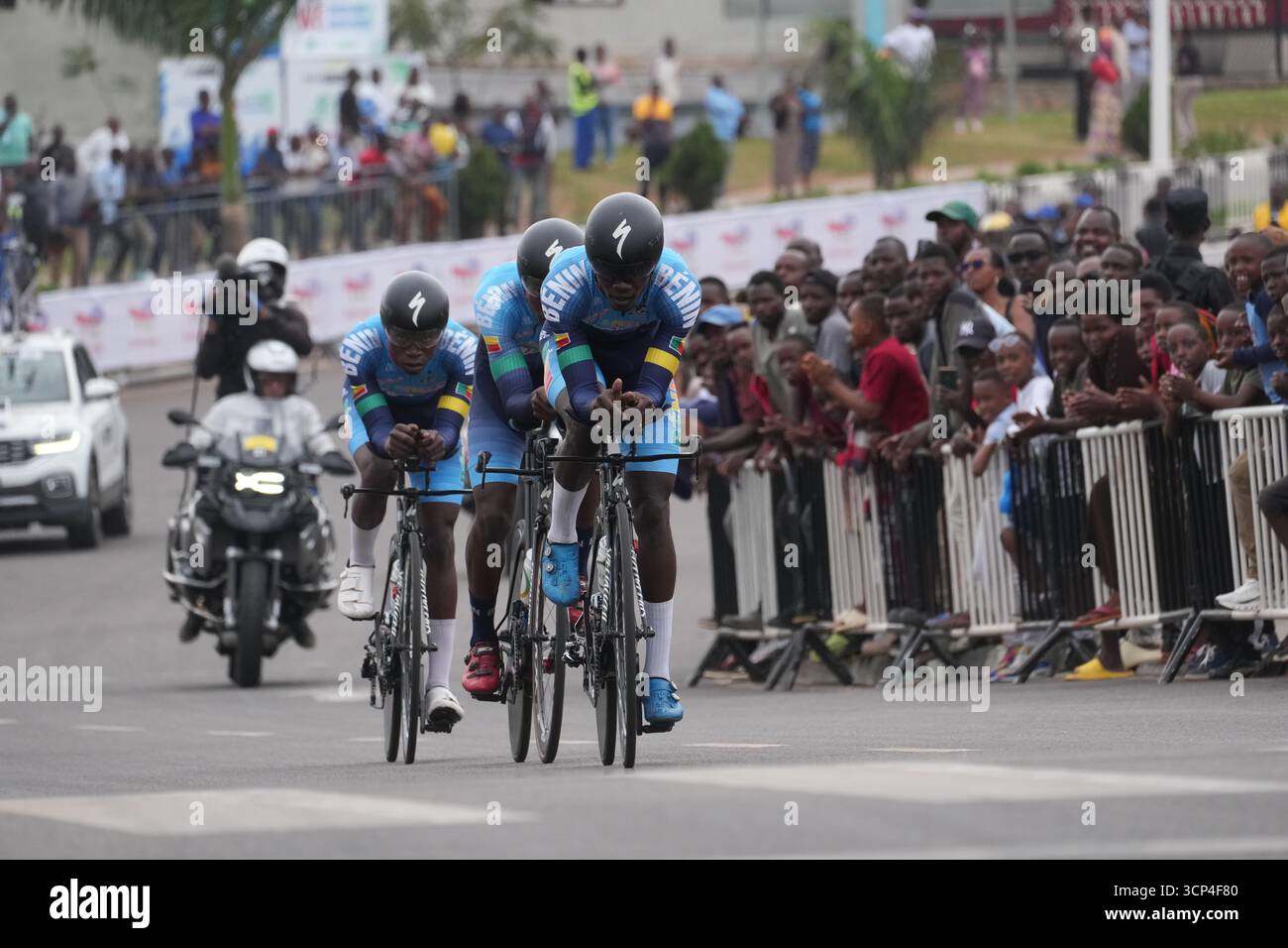 Benin cyclists ride past spectators, during the team time trial mixed ...