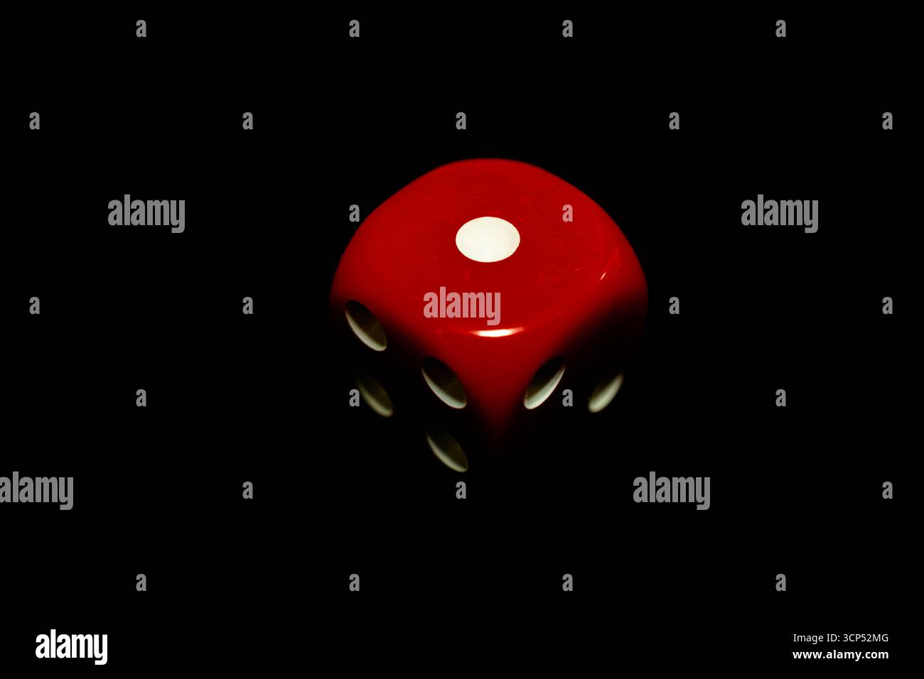 single red die showing the number one, isolated on a black background ...