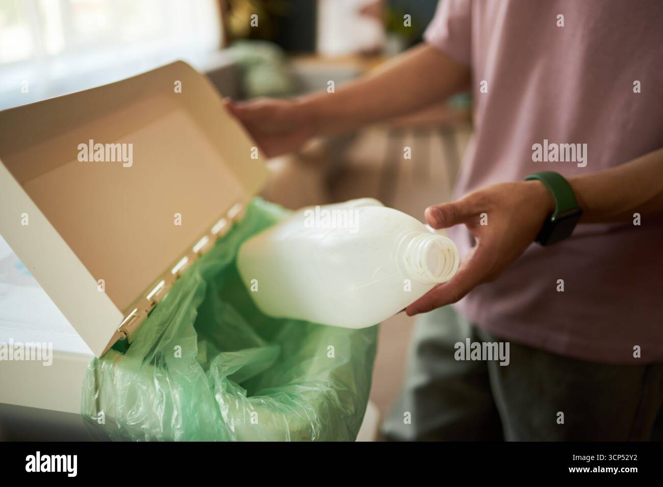 Young adult Caucasian man disposing empty plastic bottle into recycling ...