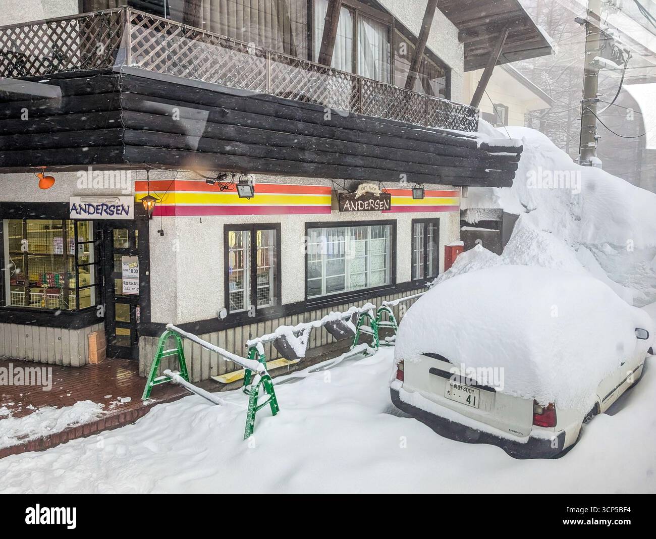 Car and building buried under deep snow after winter storm in Madarao ...