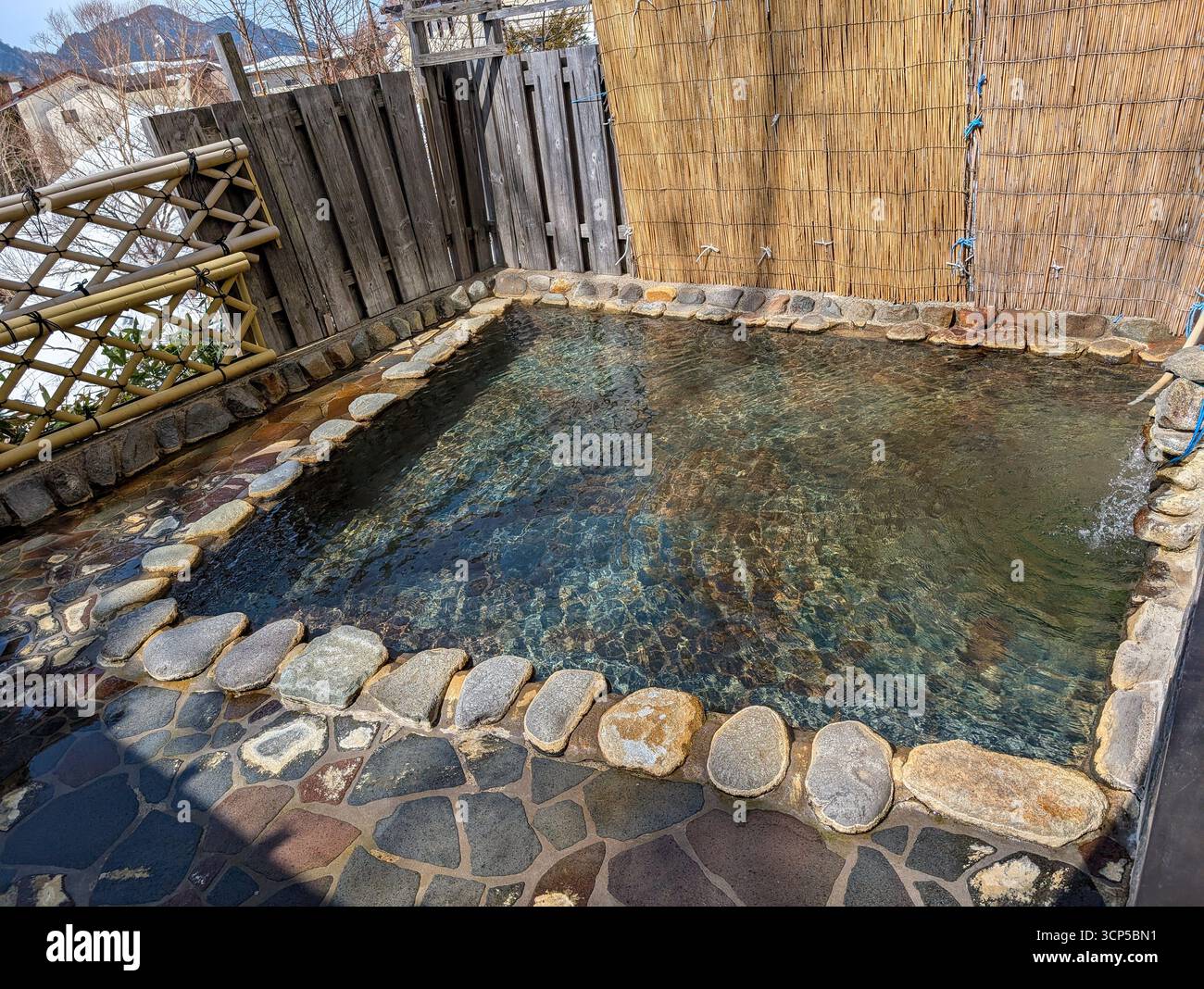Outdoor Japanese onsen hot spring bath made of stone in a snowy winter ...