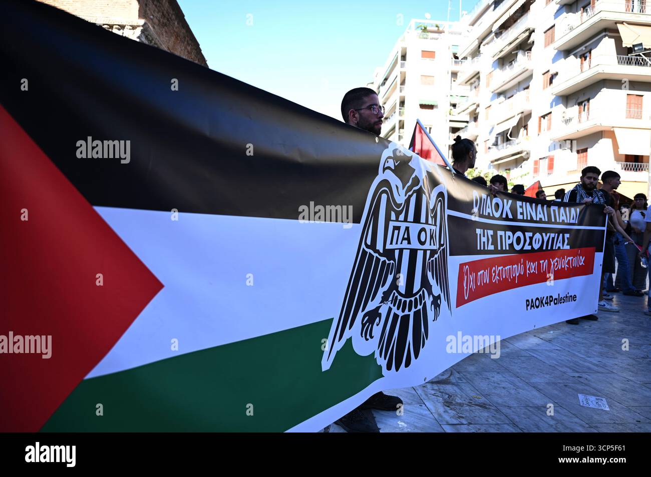 Pro-Palestinian protesters, most of them PAOK fans, hold a banner that ...