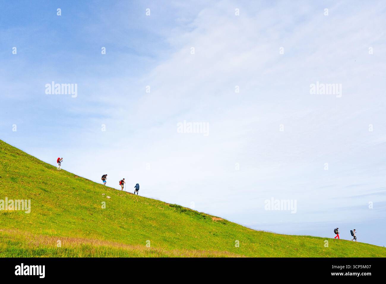 Mountaineers descending the grassy slope of Gulugod Baboy, a popular ...