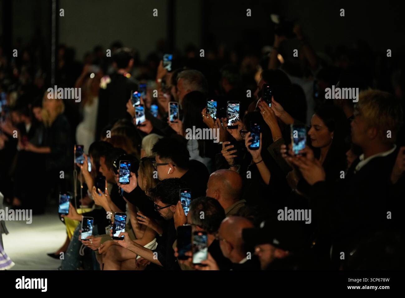 Guests use their smartphones to film and photograph models as they wear ...