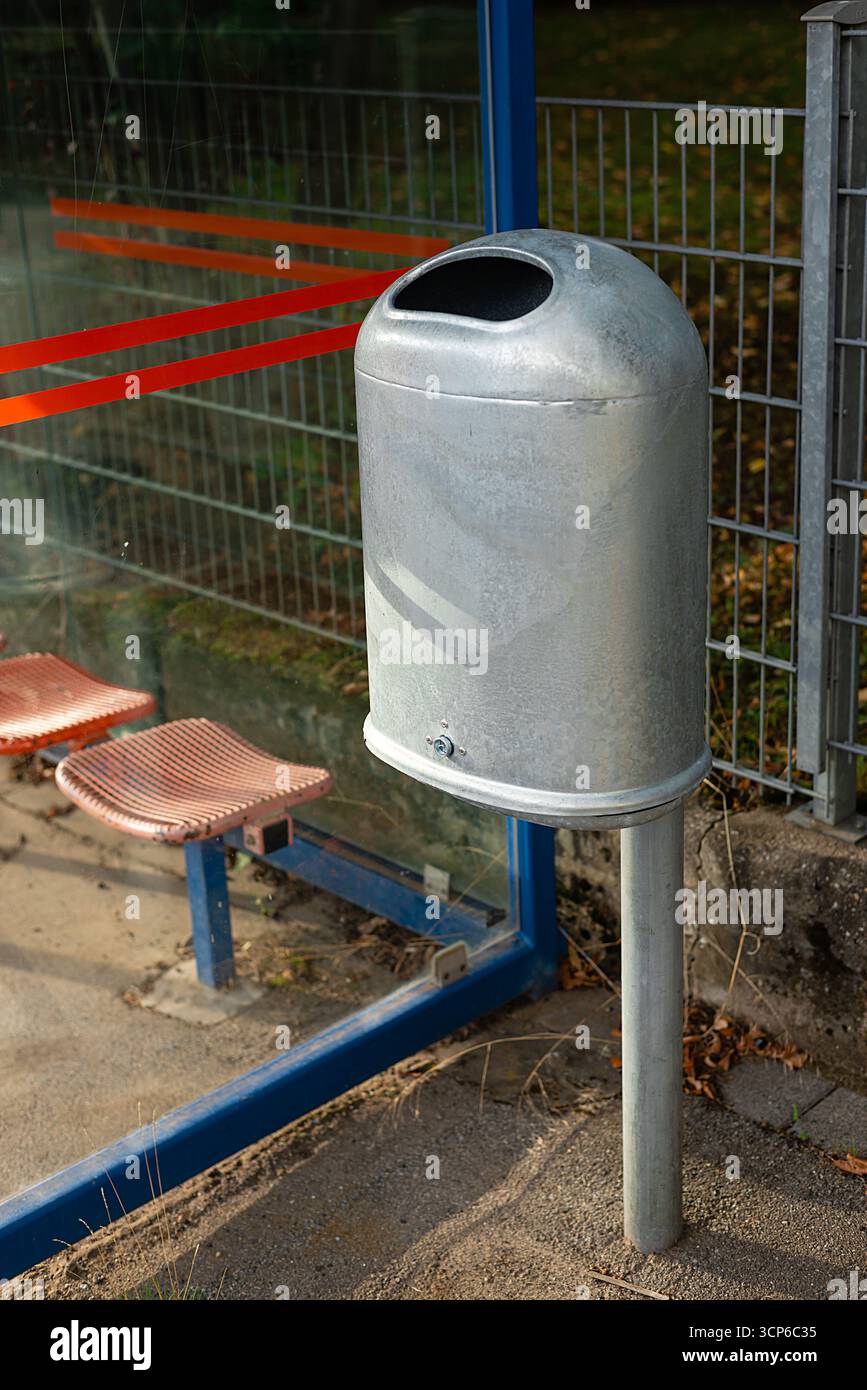 Metal trash can placed next to seats at a bus stop. Concept of ...