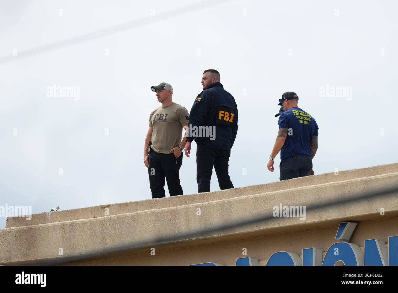 Law enforcement agents look around the roof of an apartment building ...