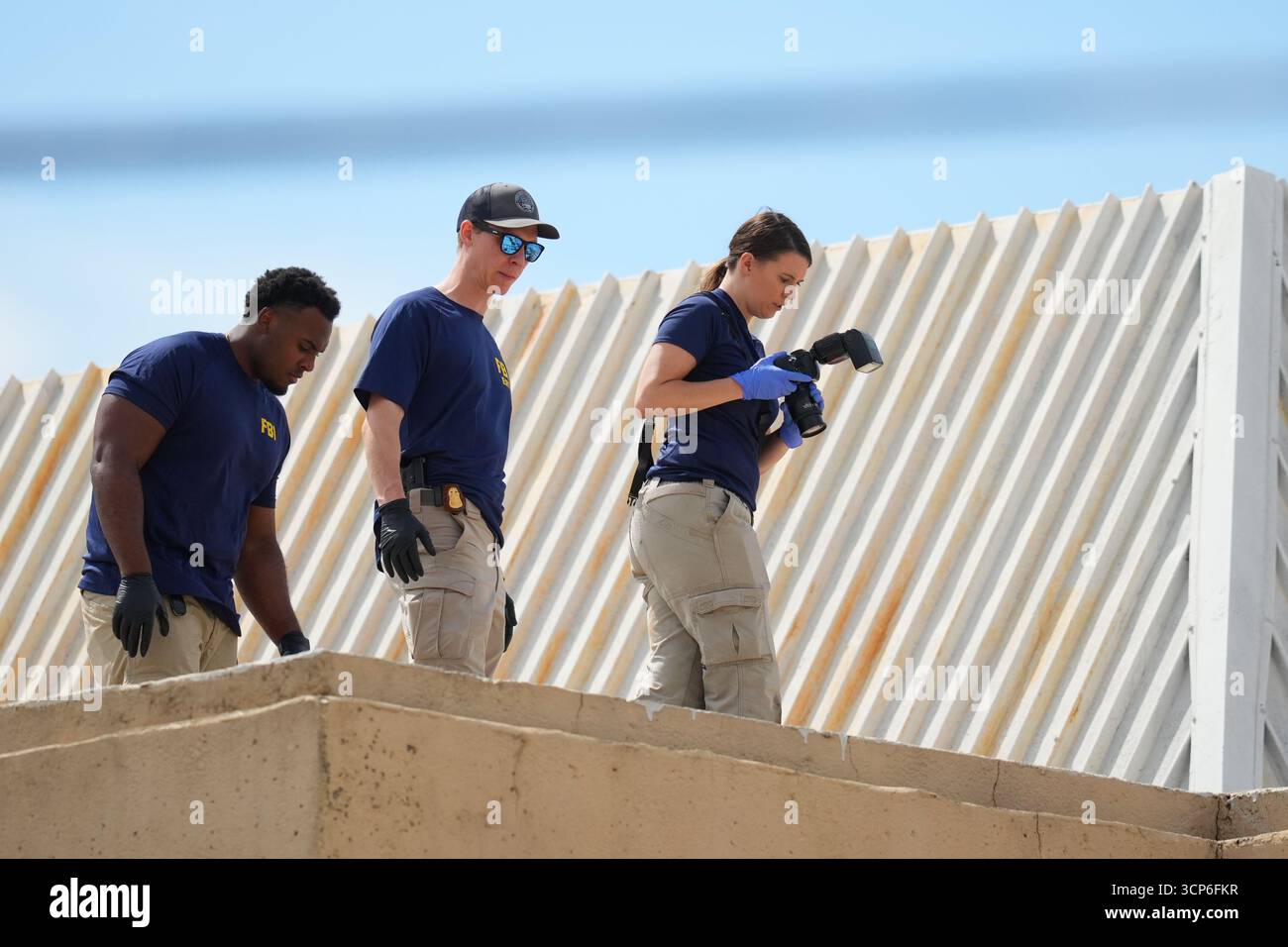 Law enforcement agents investigate the roof of an apartment building ...