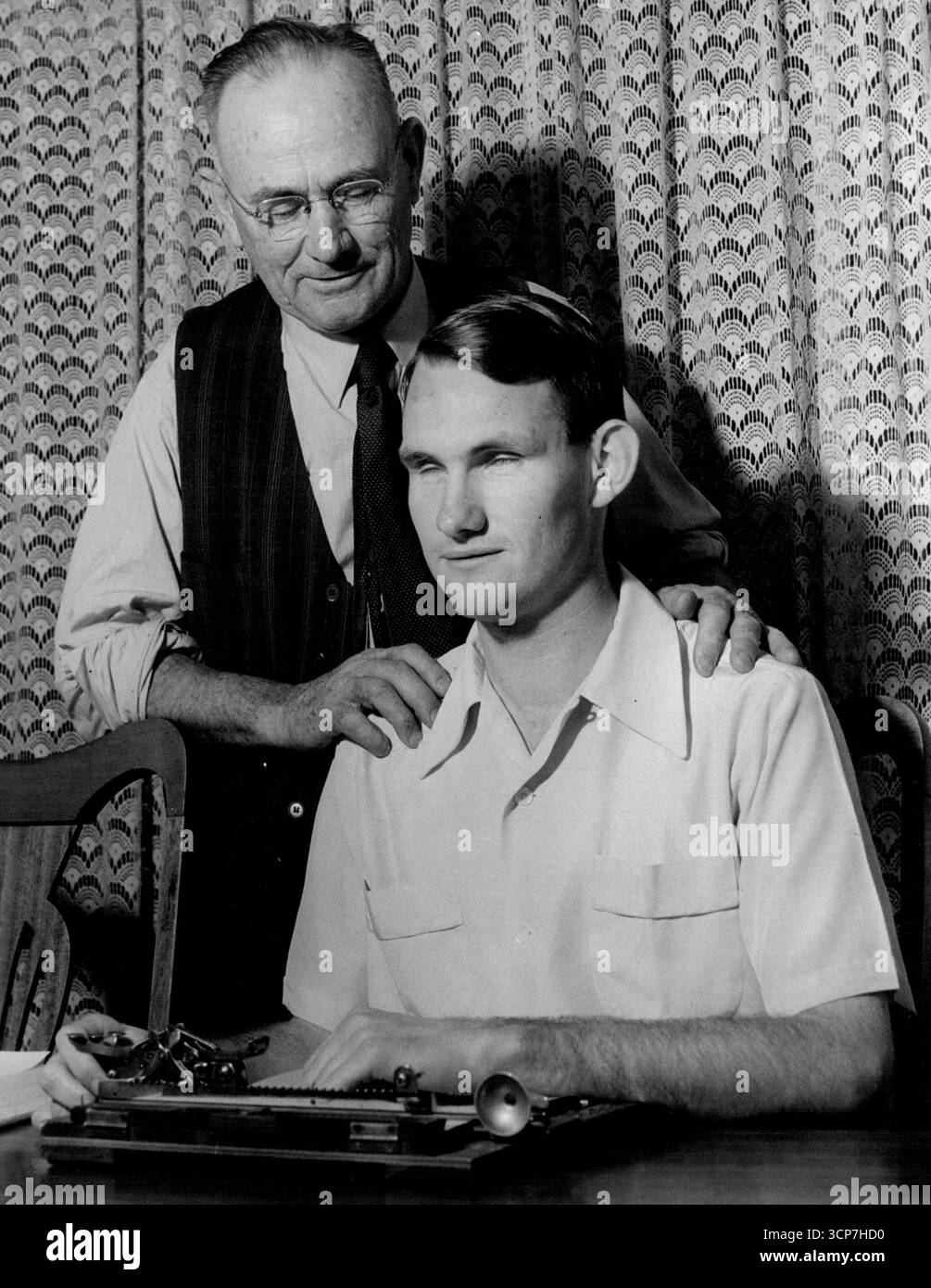 Ivan being congratulated by his father. On table is Braille machine ...