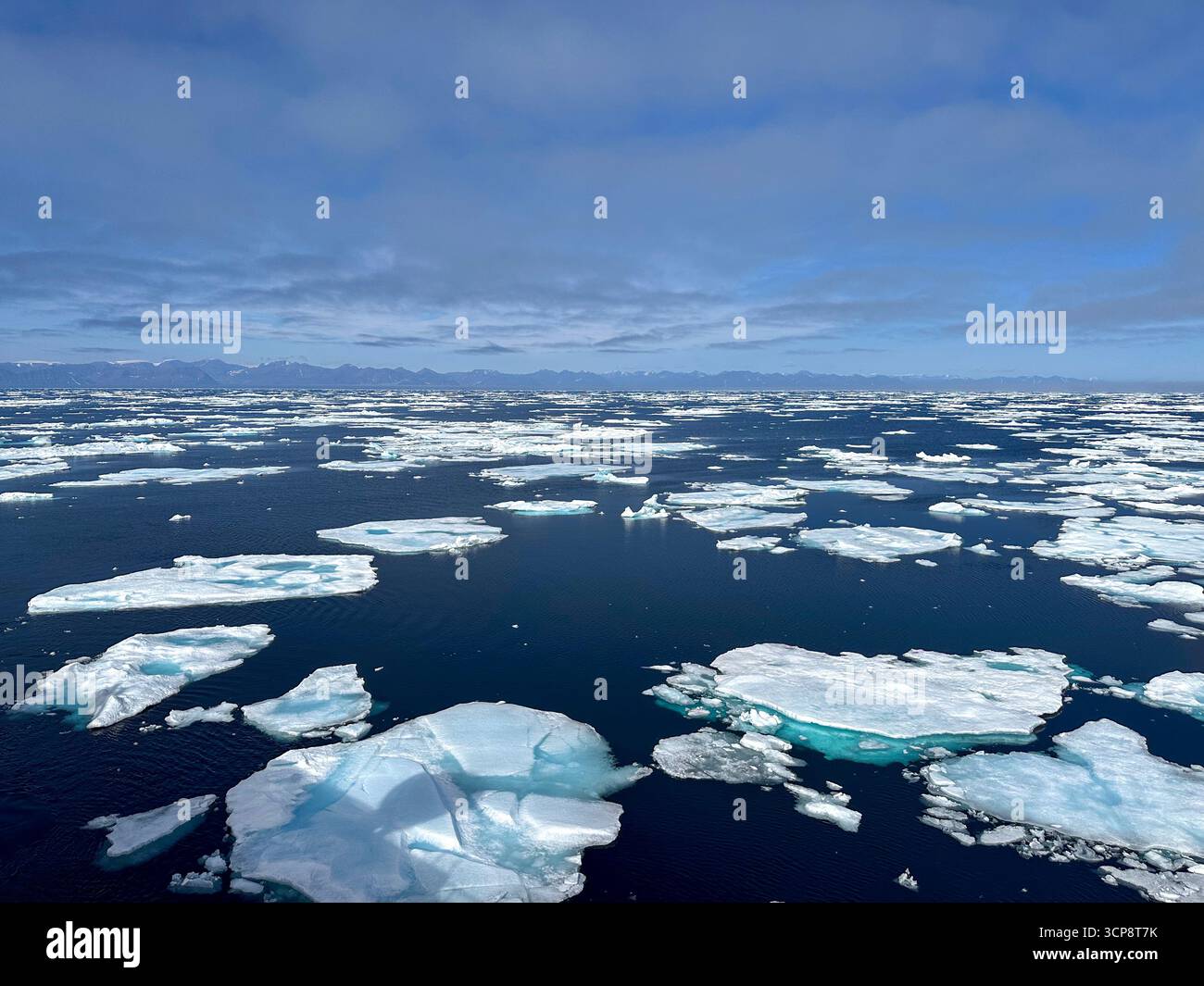 A view over a long stretch of sea ice along the coast of Greenland with ...