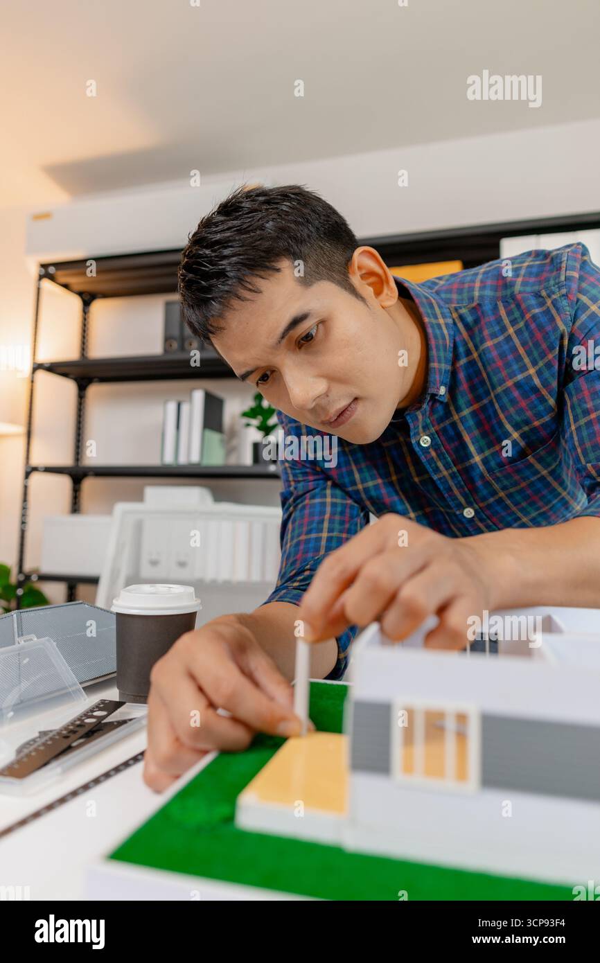A young architect works on house design plans at his desk, focusing on ...