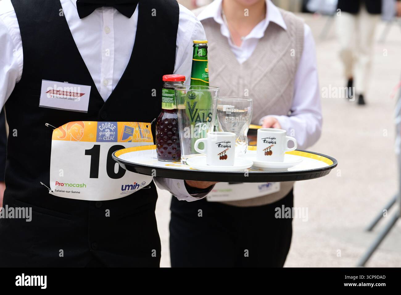 A participant carries a tray with drinks during the waiters race ...