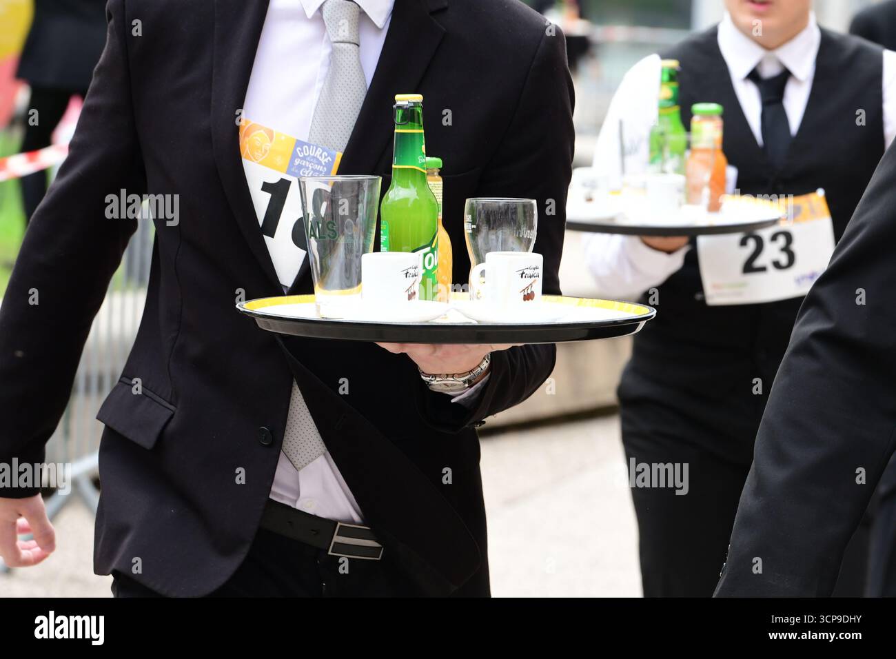 A participant carries a tray with drinks during the waiters race ...