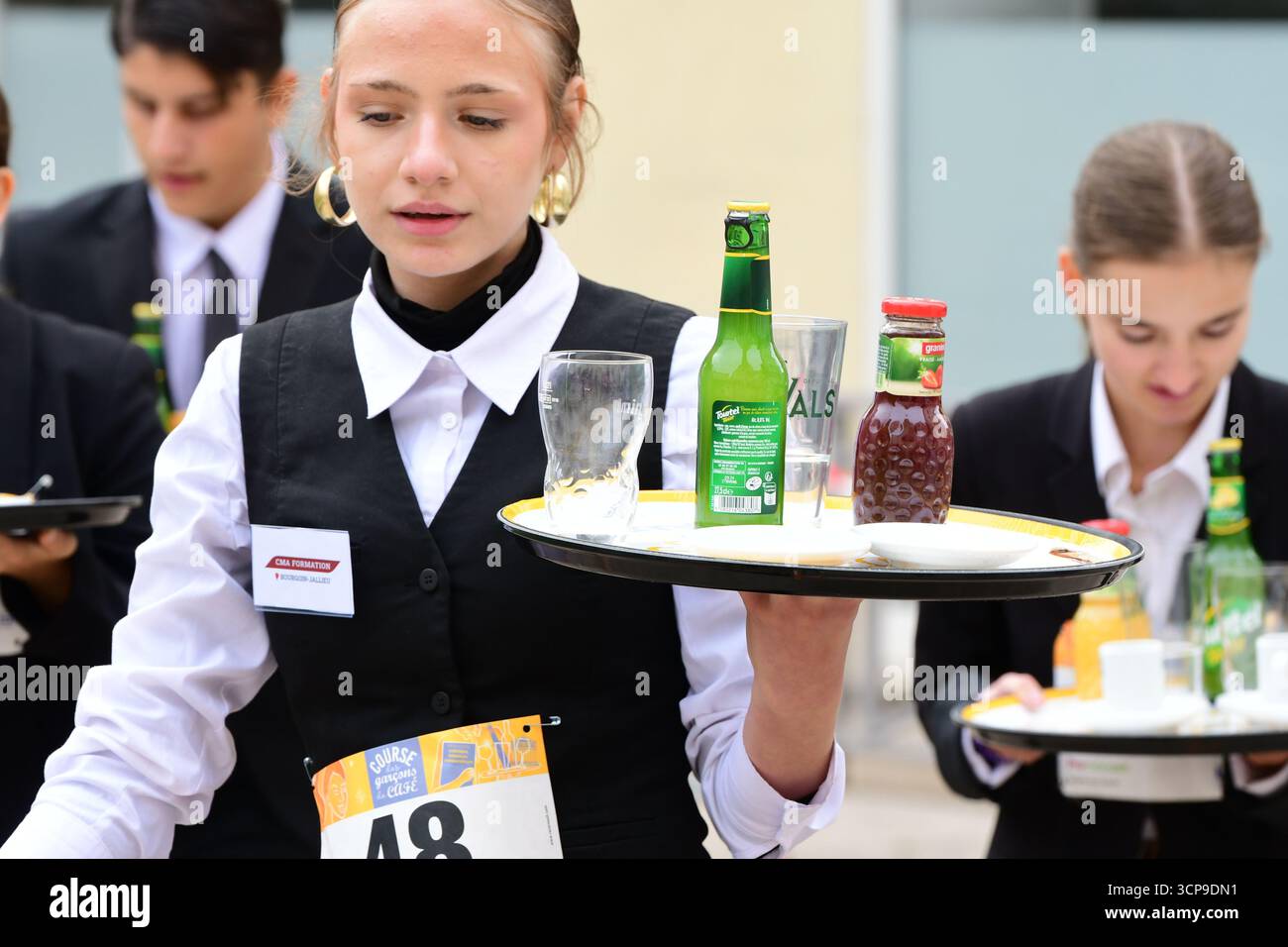 A participant carries a tray with drinks during the waiters race ...