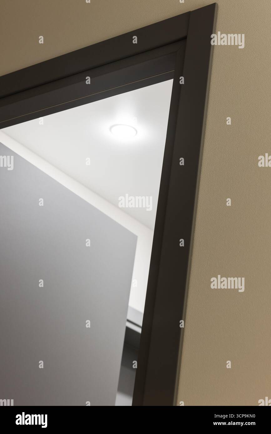 Close-up view of a modern interior door frame set into a beige wall. A ...