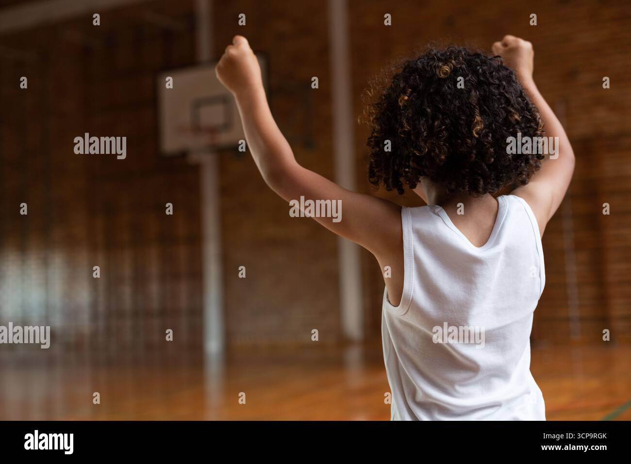 African American child raising both arms in celebration on gym ...