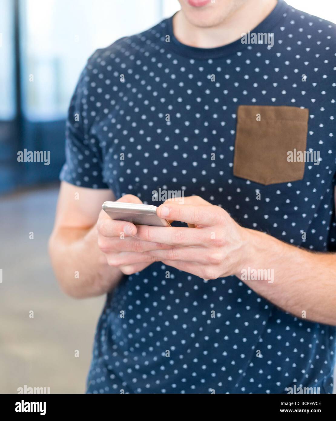 Man holding smartphone and tapping screen inside modern office corridor ...