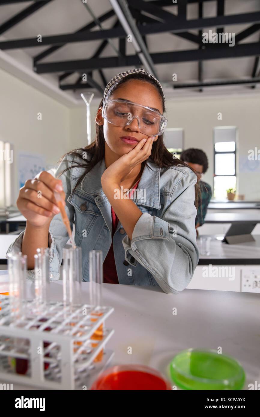 Hispanic teenage female student holding plastic dropper over test tube ...