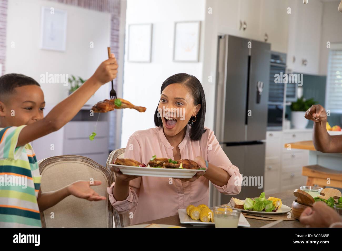 African American mother and son passing roasted chicken drumsticks ...