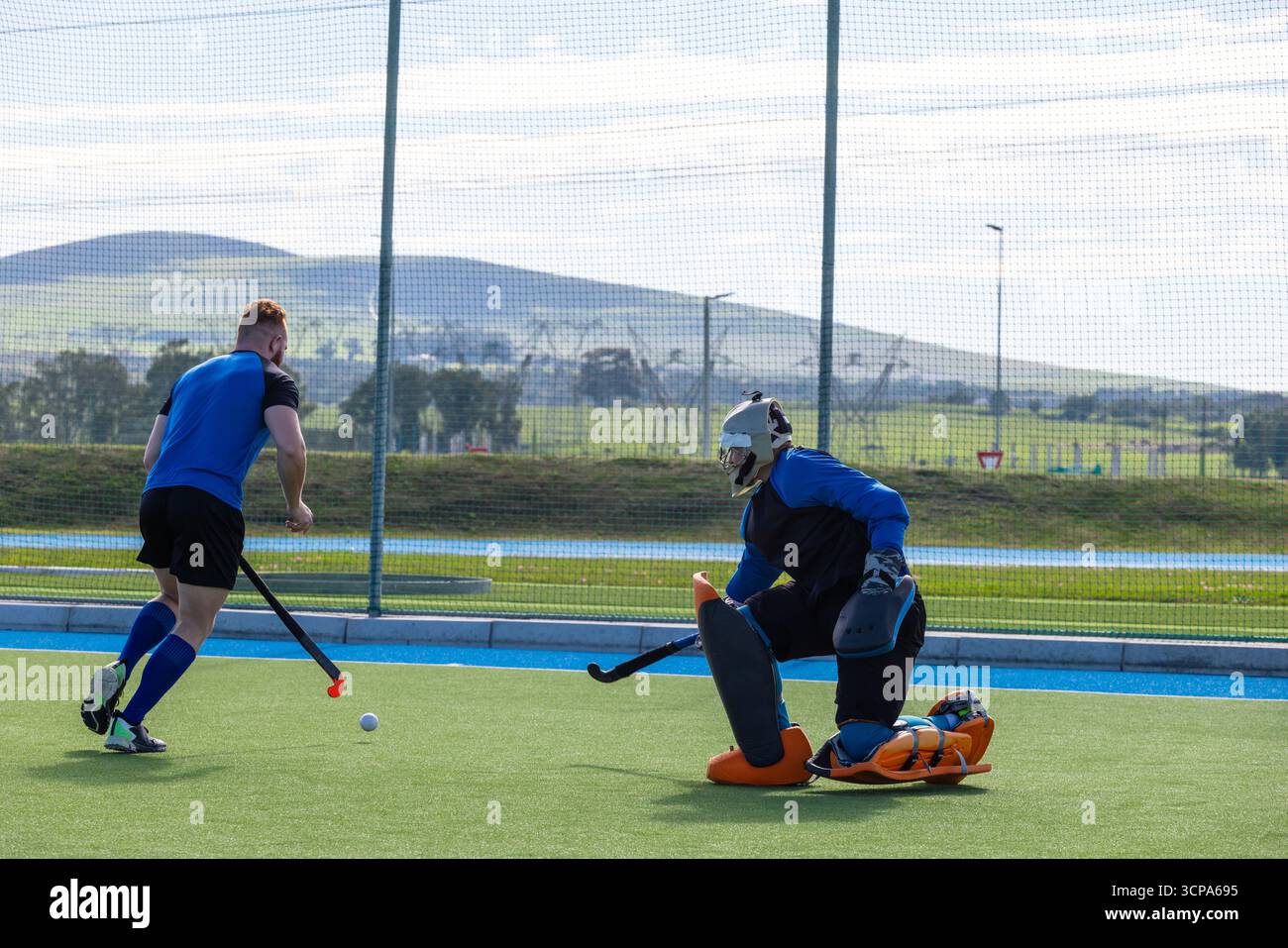 Two male field hockey players dribbling ball with sticks at crouching ...