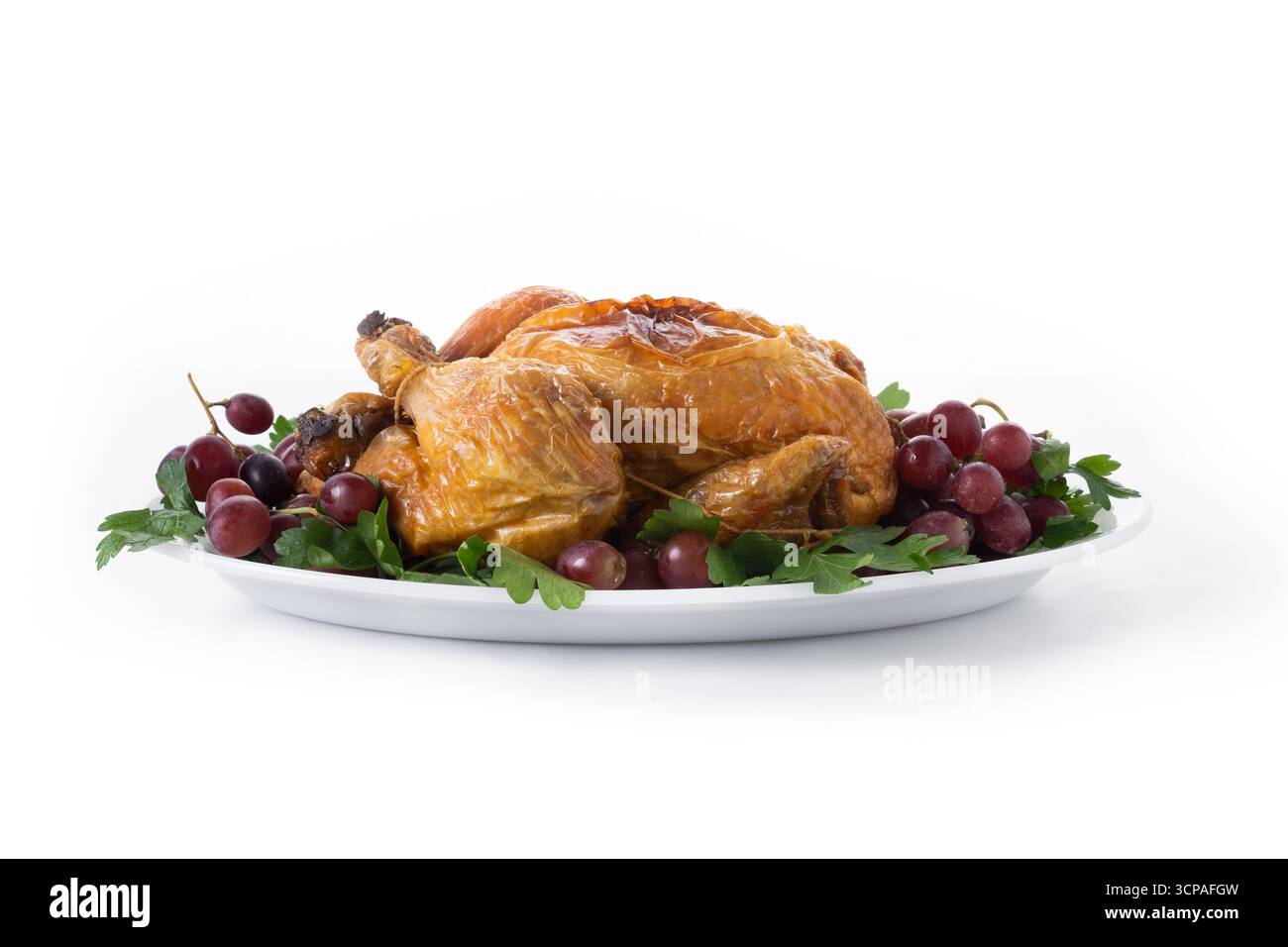 Whole roasted turkey served on a white plate, garnished with fresh ...