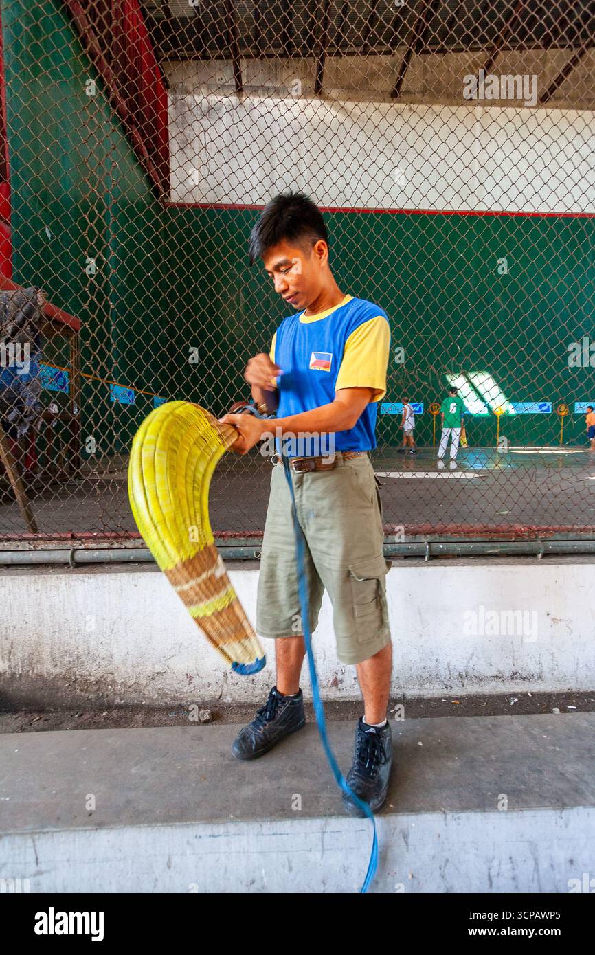 A young Filipino pelotari demonstrating how to put on his cesta at a ...