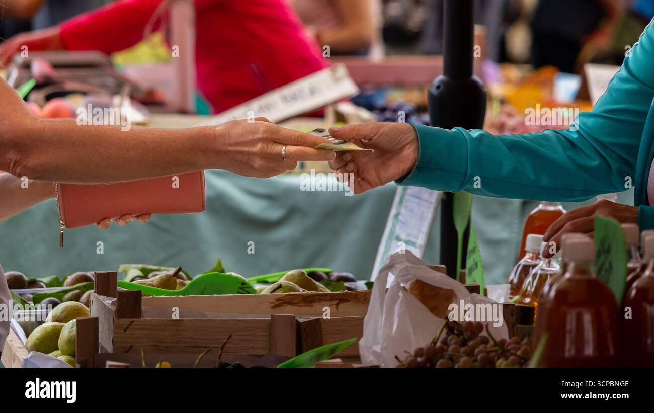 Cash transaction at outdoor market table with fruits and bottles Stock ...