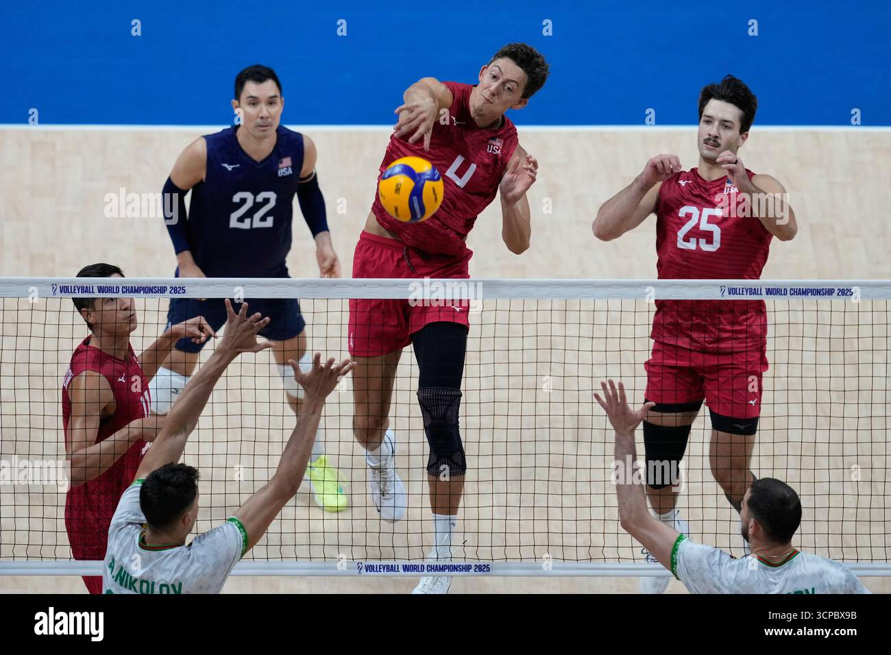 Jeffrey Jendryk II of the United States, center, spikes against ...