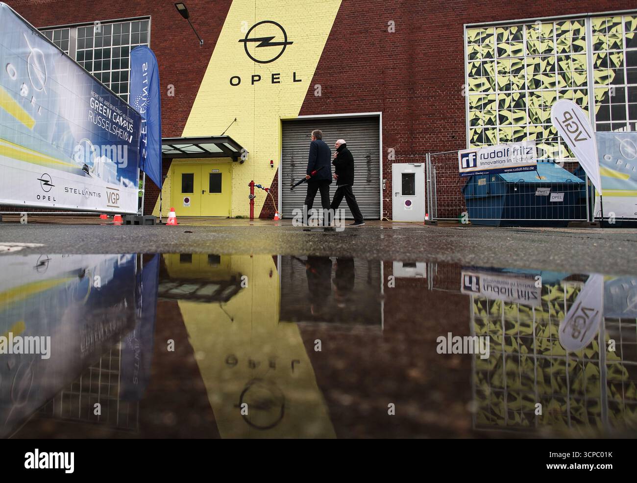 25 September 2025, Hesse, Rüsselsheim: Two people walk in front of a ...